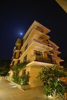 Um hotel com vários andares, varandas, entrada bem iluminada e céu noturno claro.