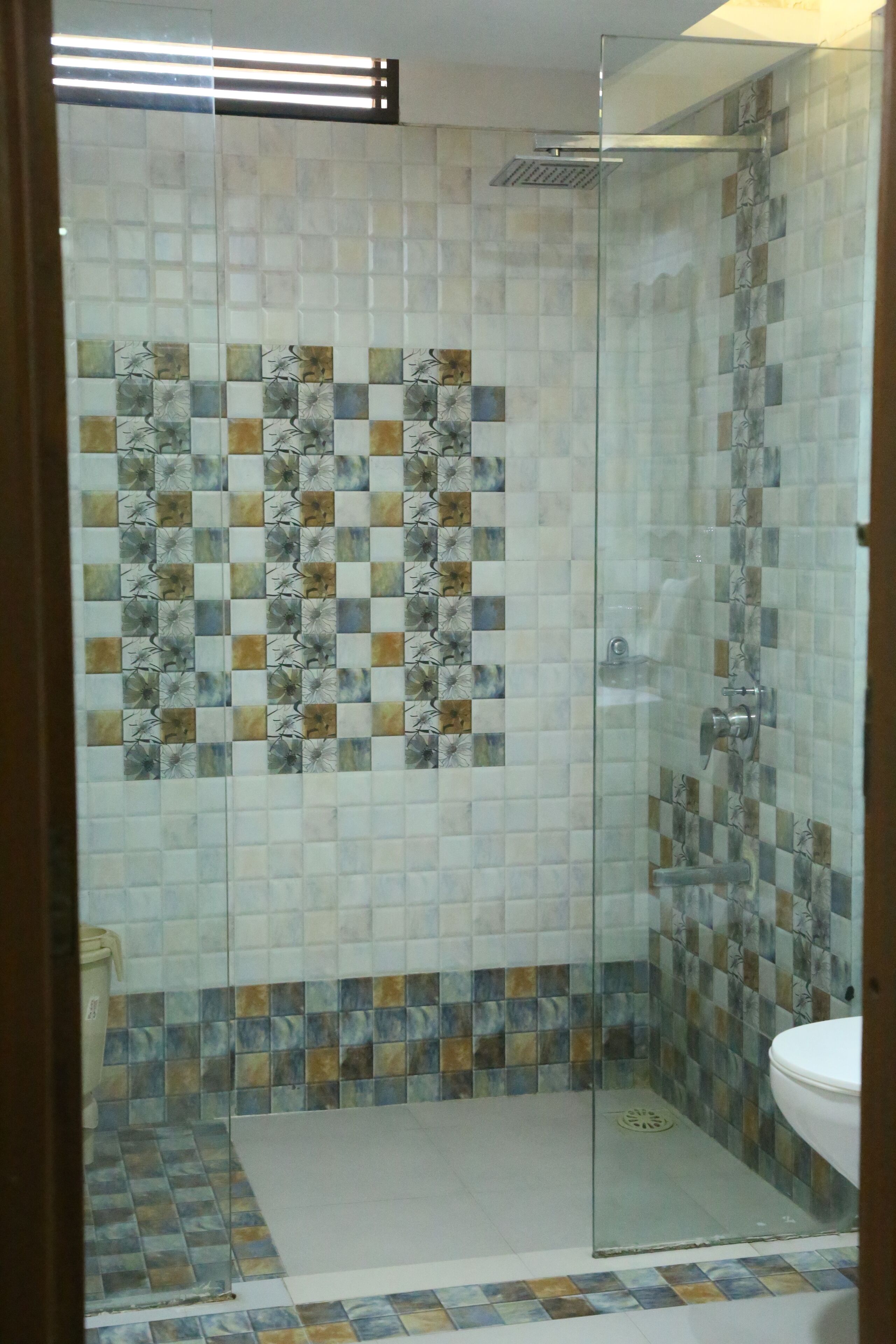 Um chuveiro com portas de vidro e paredes revestidas de azulejos.