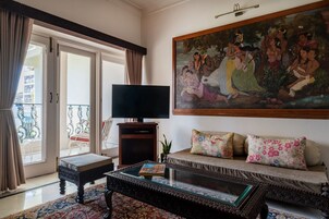Uma sala de estar com sofá, mesa de centro, televisão e um quadro.