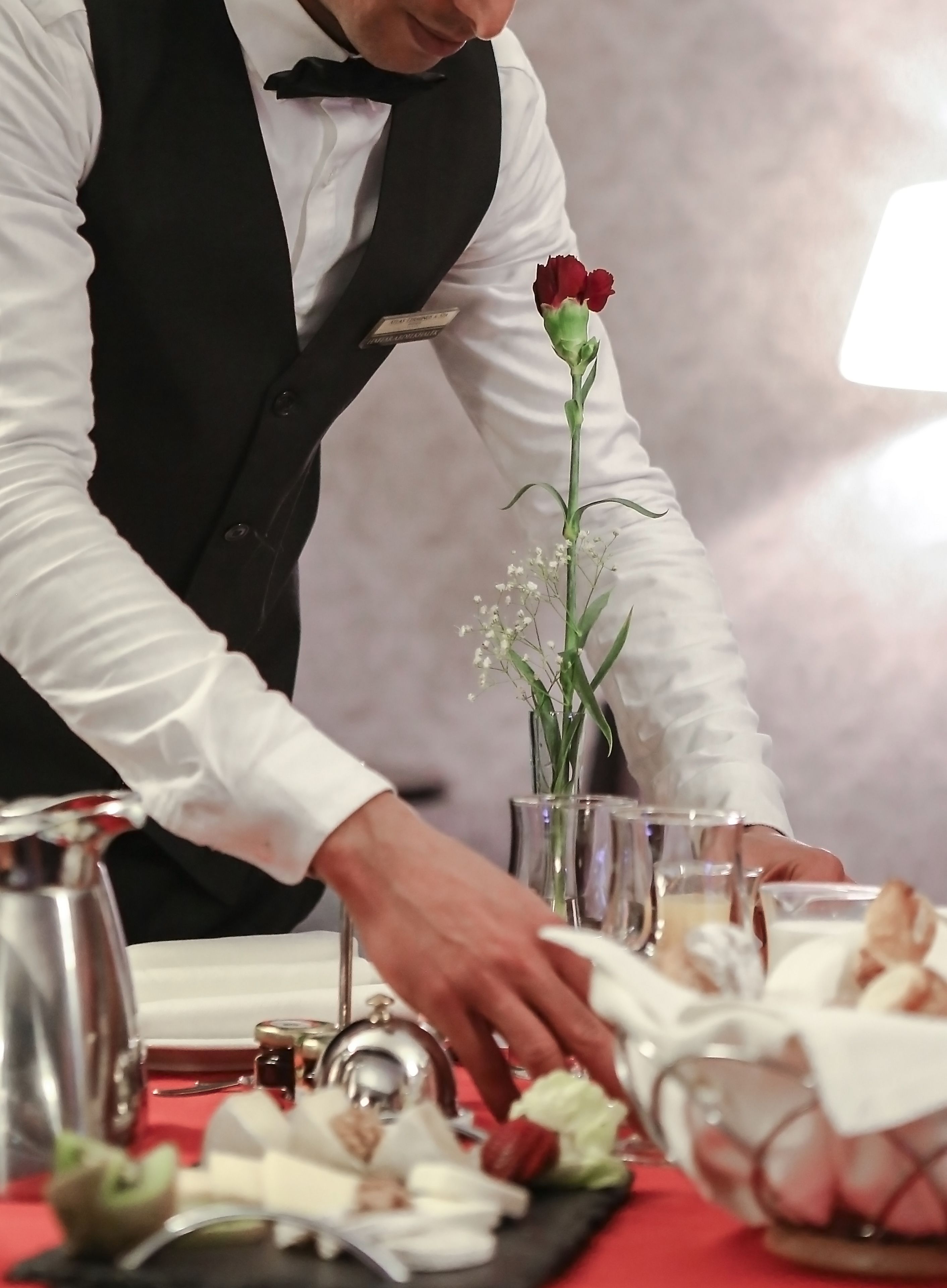 Uma pessoa organizando uma mesa com diversos alimentos e um vaso com flores.
