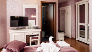 Quarto de hotel com cama, secretária, televisão de tela plana, cadeira e armário.