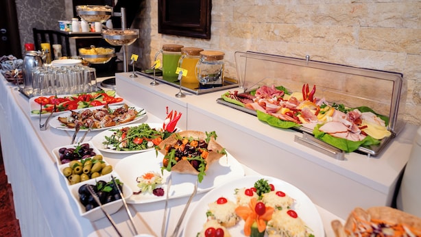 Buffet variado com saladas, carnes e queijos.