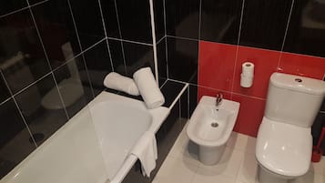Uma casa de banho moderna com banheira, bidé e sanita.