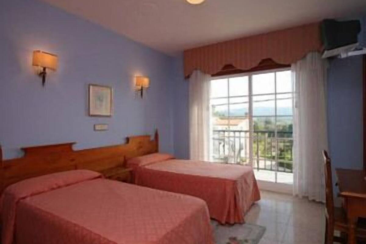 Quarto de hotel com duas camas, varanda e vista para a paisagem.