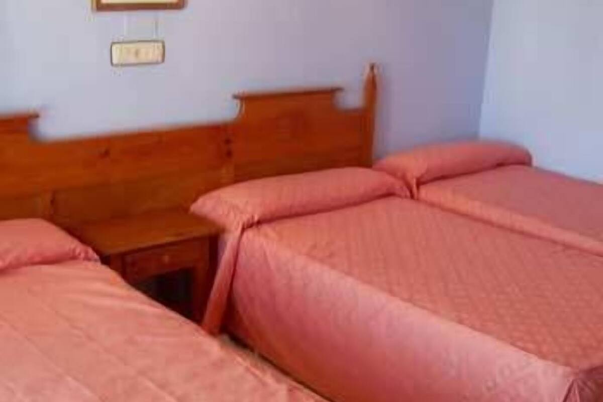 Quarto com duas camas de solteiro, cabeceiras de madeira e uma pequena mesa de cabeceira.