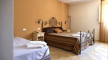 Um quarto com cama, mesa de cabeceira, abajur e janela com cortinas.