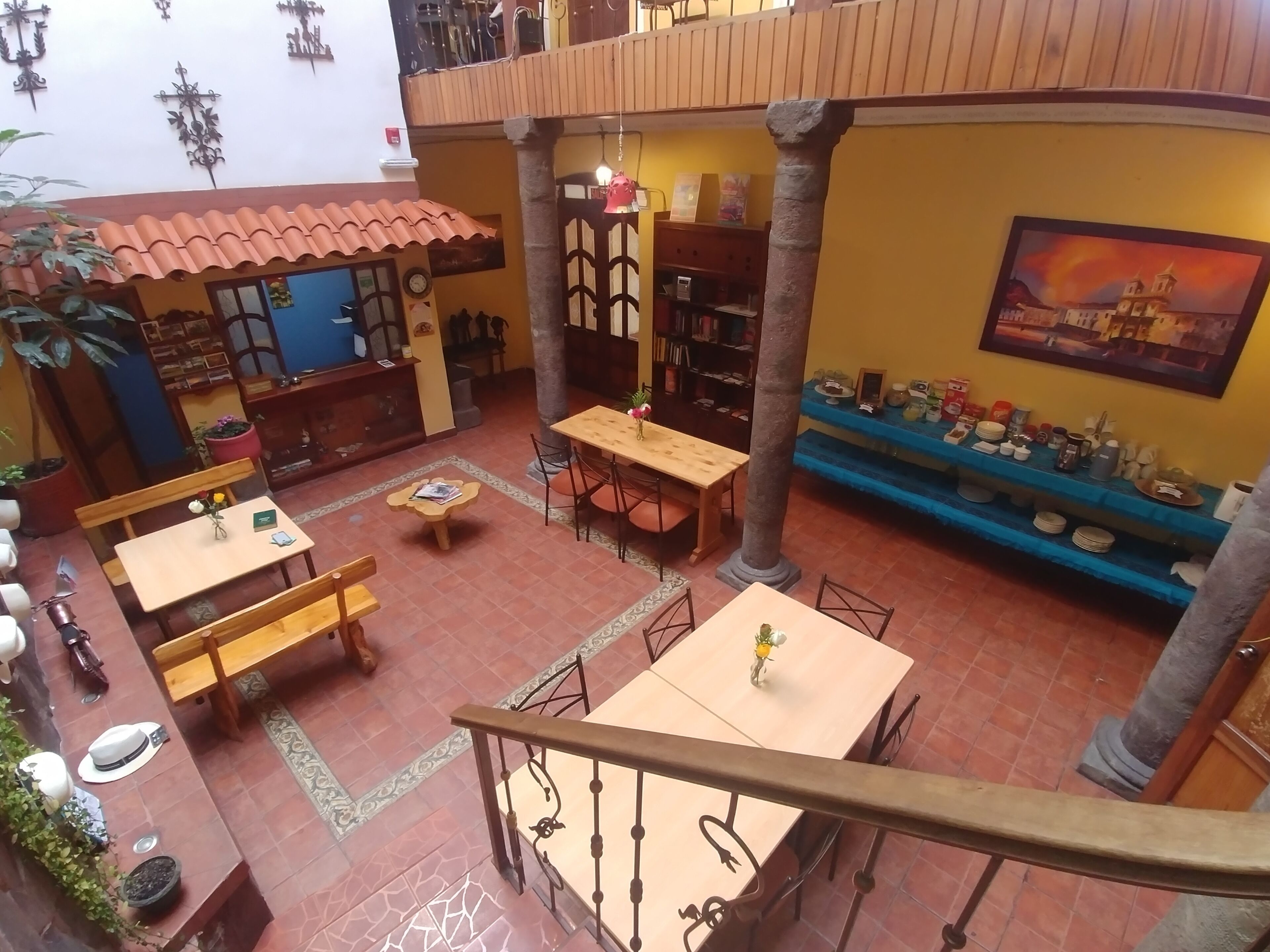 Um pátio amplo com vários espaços para sentar, uma mesa central e uma estante.