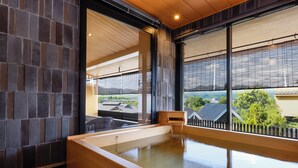 Um spa moderno com uma banheira de madeira, grandes janelas e vista para os arredores.