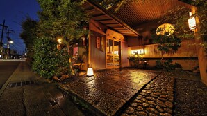 Um edifício japonês tradicional com entrada de madeira e um candeeiro no chão.