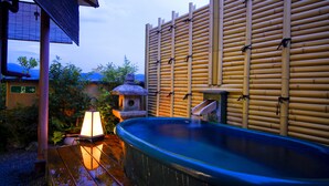 Uma banheira de hidromassagem com um fundo de bambu, um lampião de pedra e um deck de madeira.