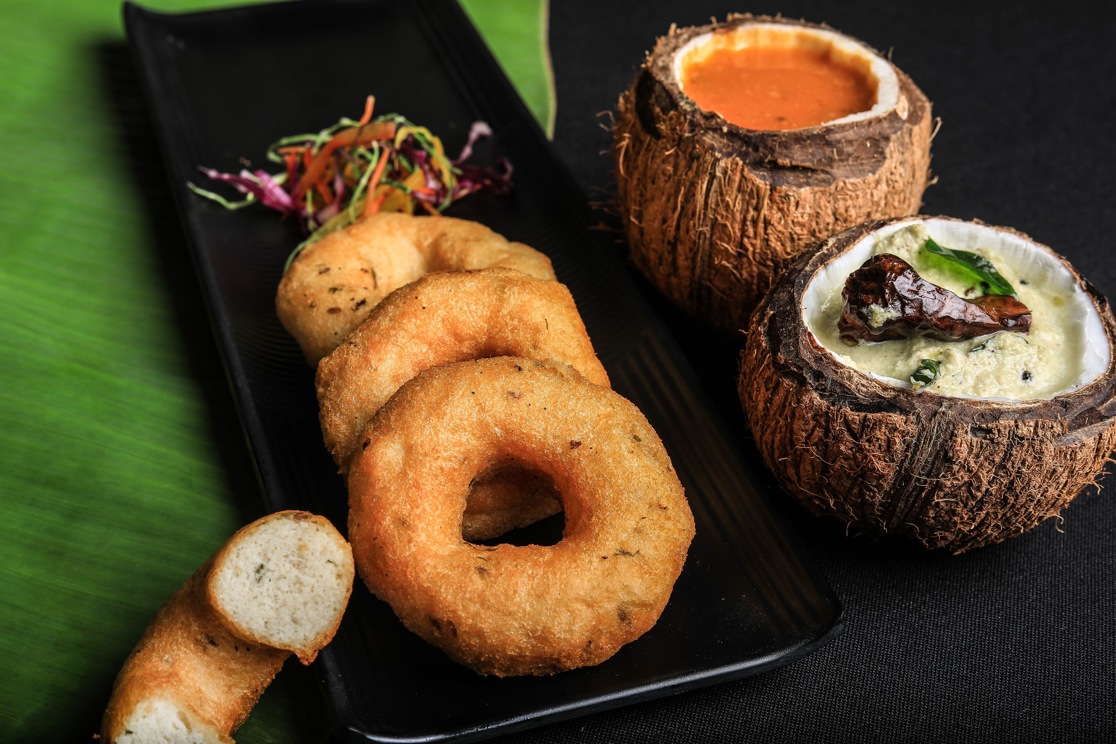 Um prato com bolinhos fritos, um coco com molho e uma salada.