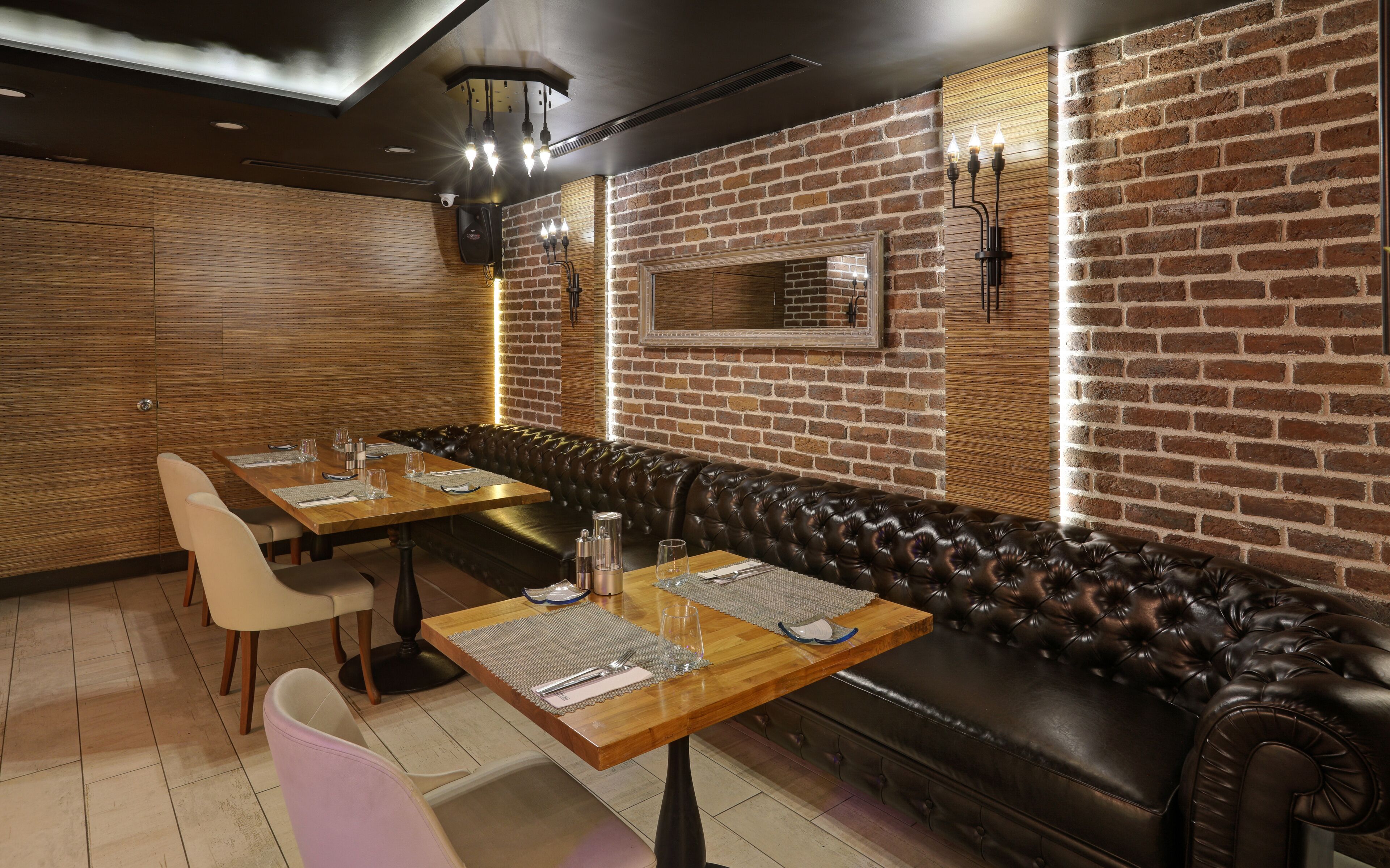 Restaurante com parede de tijolos, painéis de madeira, assentos em cabines de couro e mesa de madeira posta para refeição.