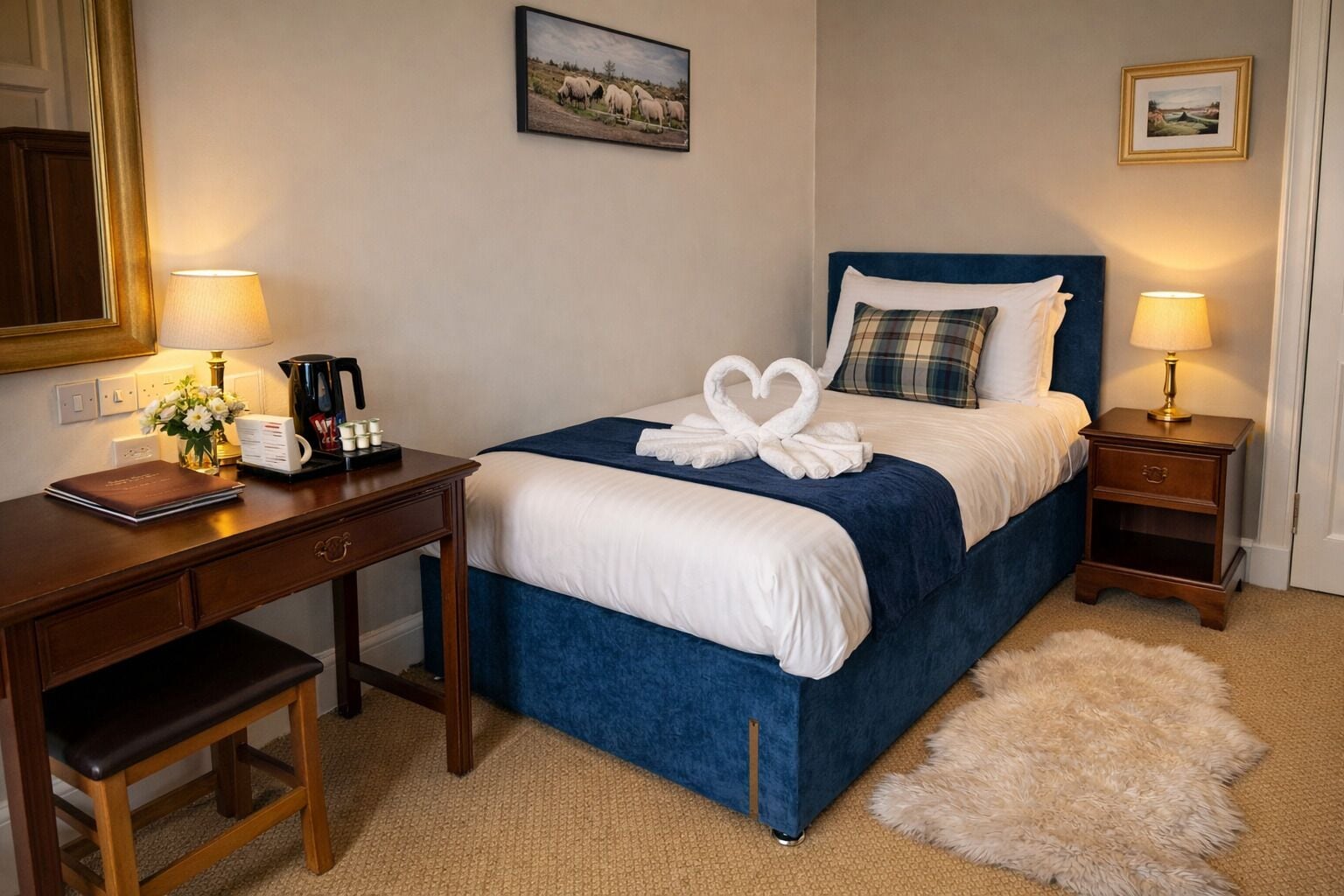 Quarto de hotel bem arrumado, com cama, mesas de cabeceira, escrivaninha e uma cadeira.