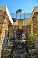 Entrada de um hotel com uma cascata de pedra e uma placa com a inscrição 'Premier Hotel El Paso'.