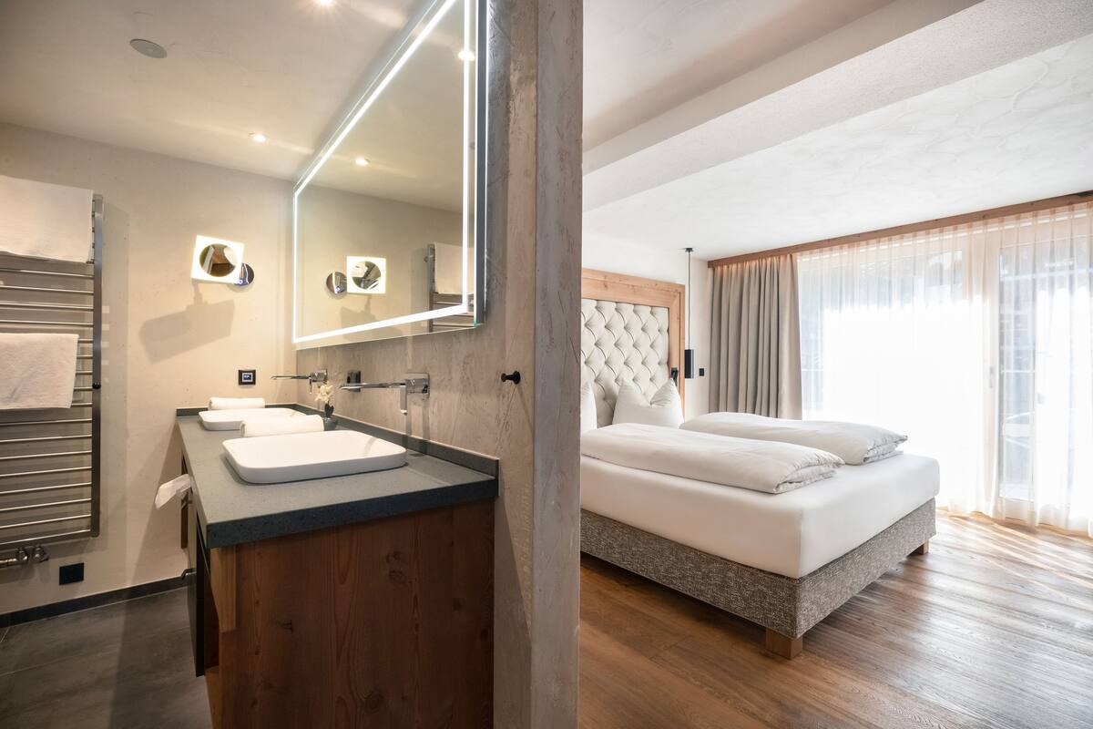 Uma casa de banho moderna com toucador de madeira, um espelho grande e um porta-toalhas.