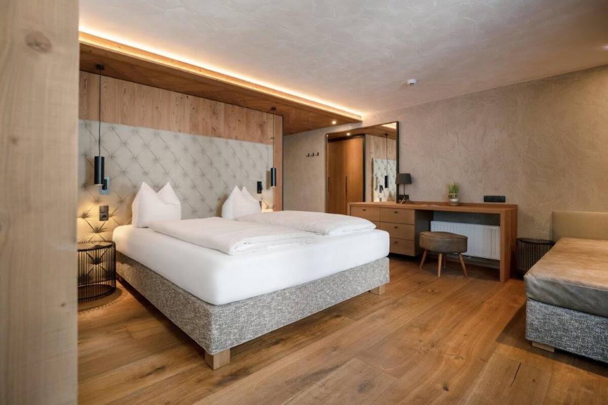 Quarto moderno com uma cama grande, uma escrivaninha de madeira e um espelho.