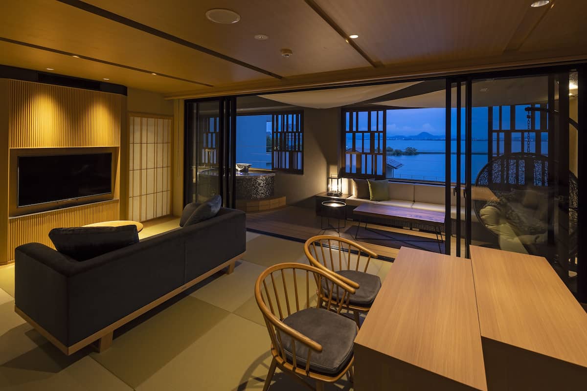 Uma sala de estar moderna com sofá, cadeiras, televisão e uma mesa de jantar.