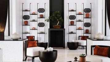 Uma sala de estar moderna com lareira, móveis em preto e branco e estantes decorativas com vasos e plantas.