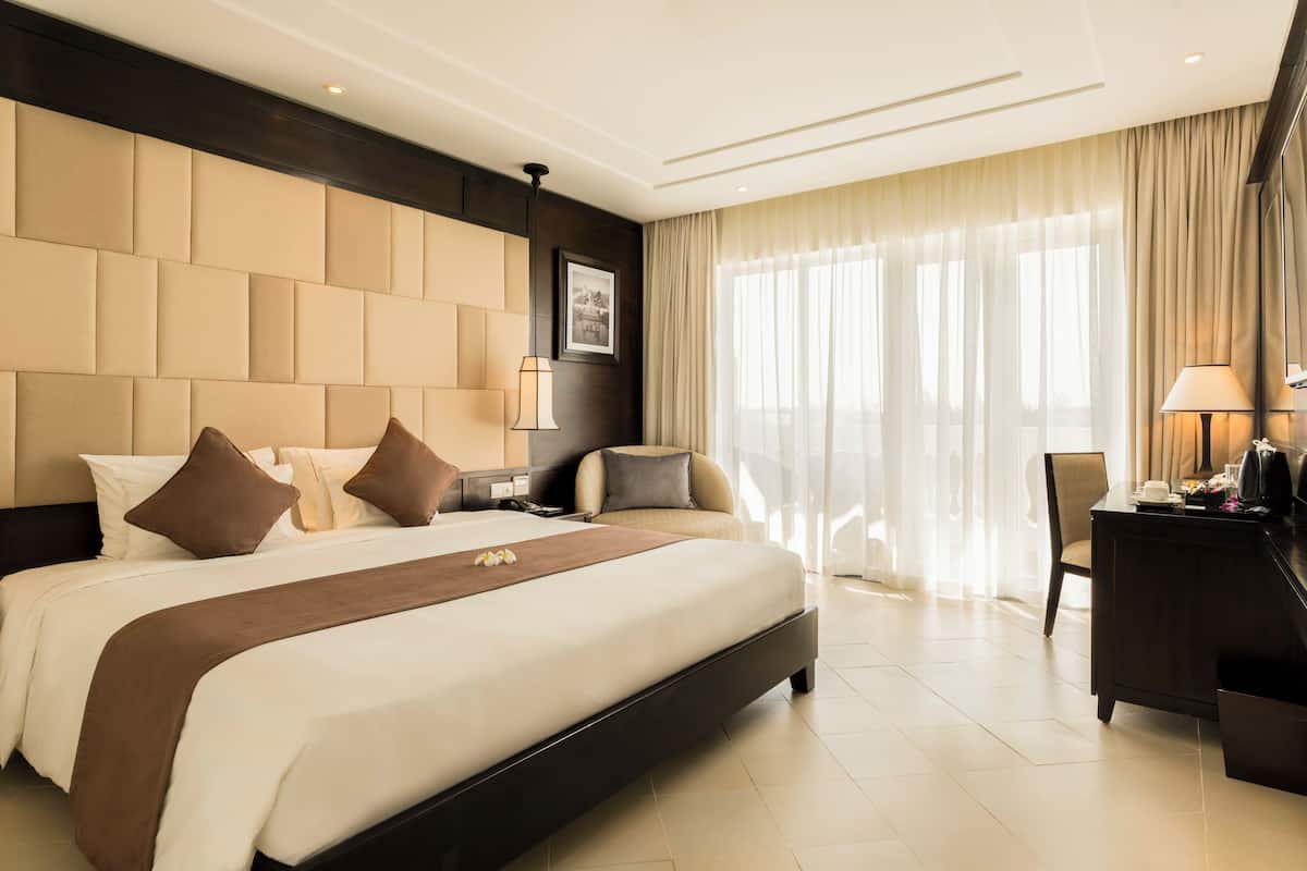 Quarto de hotel com uma cama grande, uma escrivaninha e uma cadeira.