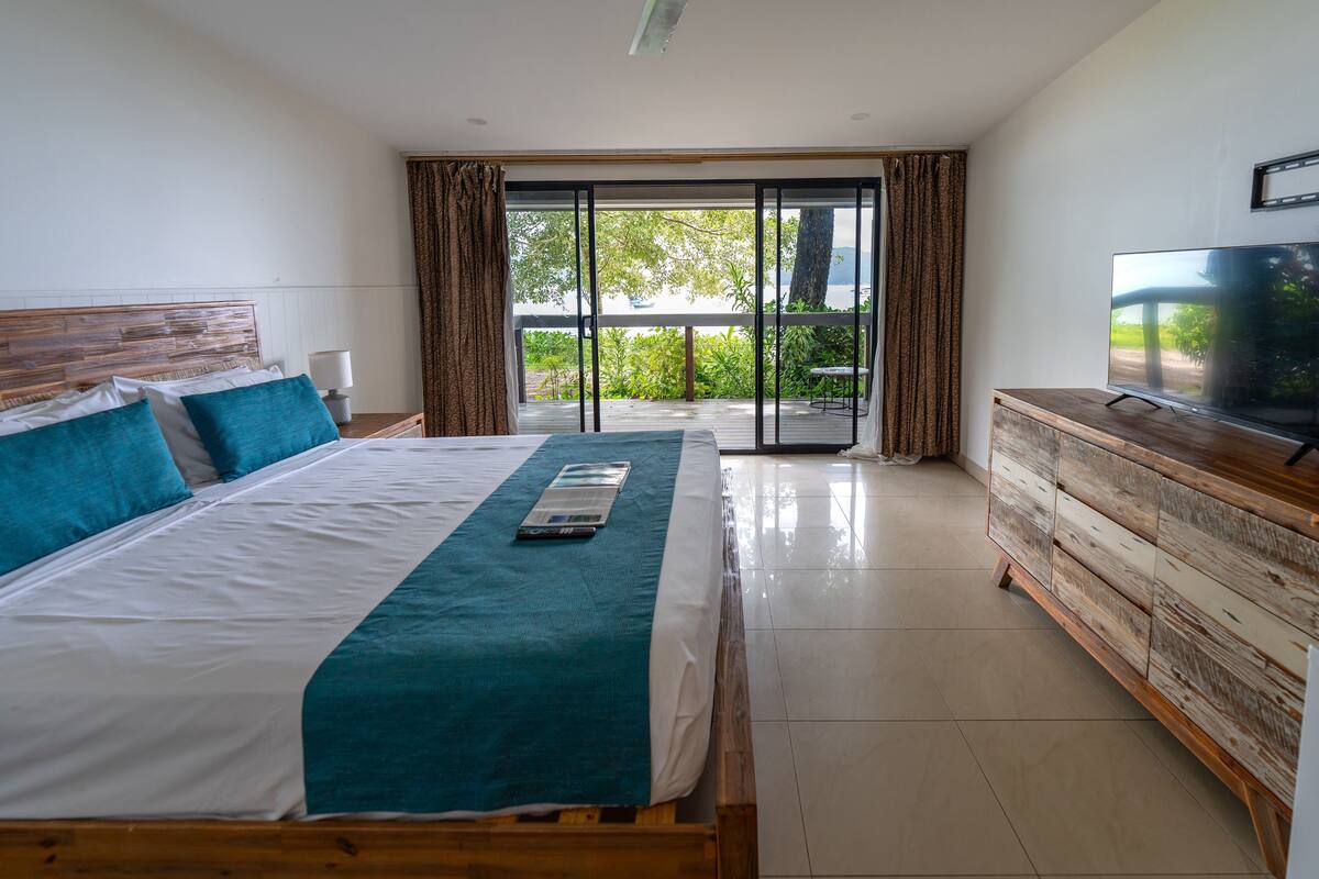 Quarto com uma cama grande, televisão e vista para o exterior.