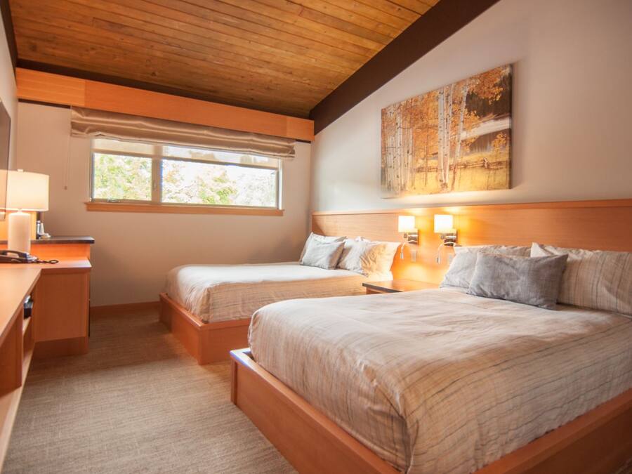 Quarto com duas camas, uma escrivaninha, um abajur e um quadro na parede.