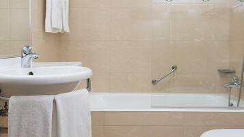 Um banheiro com pia, banheira e vaso sanitário. Toalhas penduradas em um porta-toalhas.