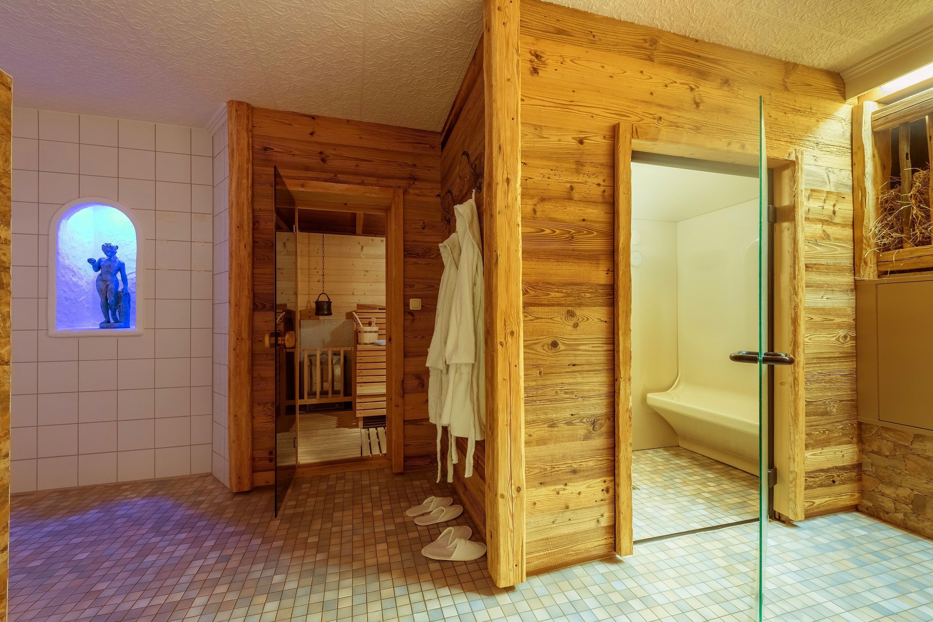 Casa de banho estilo cabana de madeira com banheira, chuveiro e uma pequena janela com uma estátua.