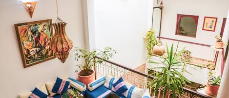 Uma sala de estar aconchegante com um sofá, plantas em vasos e um lustre.