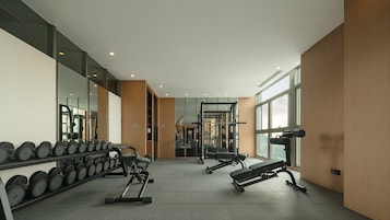 Uma academia moderna com equipamentos de musculação, espelhos e grandes janelas.