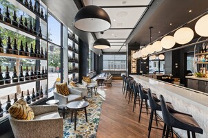 Uma área de bar moderna com prateleiras de garrafas, assentos e iluminação pendente.