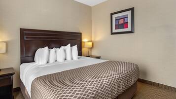 Quarto de hotel com uma cama grande, uma mesa de cabeceira, um abajur e um quadro na parede.