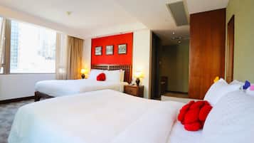 Quarto de hotel com duas camas, uma parede de destaque vermelha e uma janela grande.