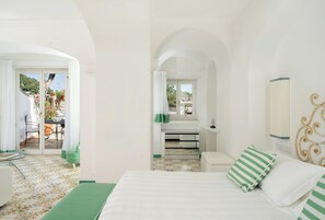 Quarto com cama, escrivaninha e vista para o exterior.