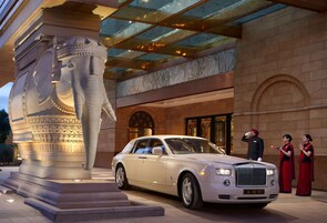 Um Rolls Royce estacionado em frente a um edifício com uma estátua de elefante.