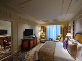 Quarto de hotel com uma cama grande, televisão, escrivaninha com computador e uma cadeira.