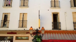 Um hotel com várias varandas, um toldo vermelho e uma cesta de flores suspensa.