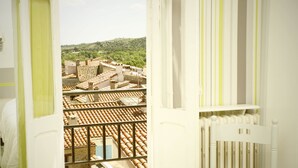 Quarto com vista para telhados de terracota por uma porta aberta.