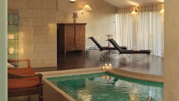 Área de piscina com espreguiçadeiras, um armário de madeira e luminárias fixadas na parede.