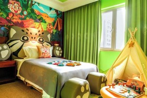 Quarto de criança com cama, janela verde, uma tenda e um mural na parede.