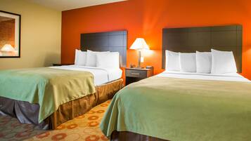 Quarto de hotel com duas camas, cada uma com cabeceira, mesa de cabeceira e luminária.