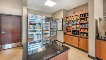 Uma estação de autoatendimento com dispensadores de bebidas refrigeradas e diversos lanches embalados.