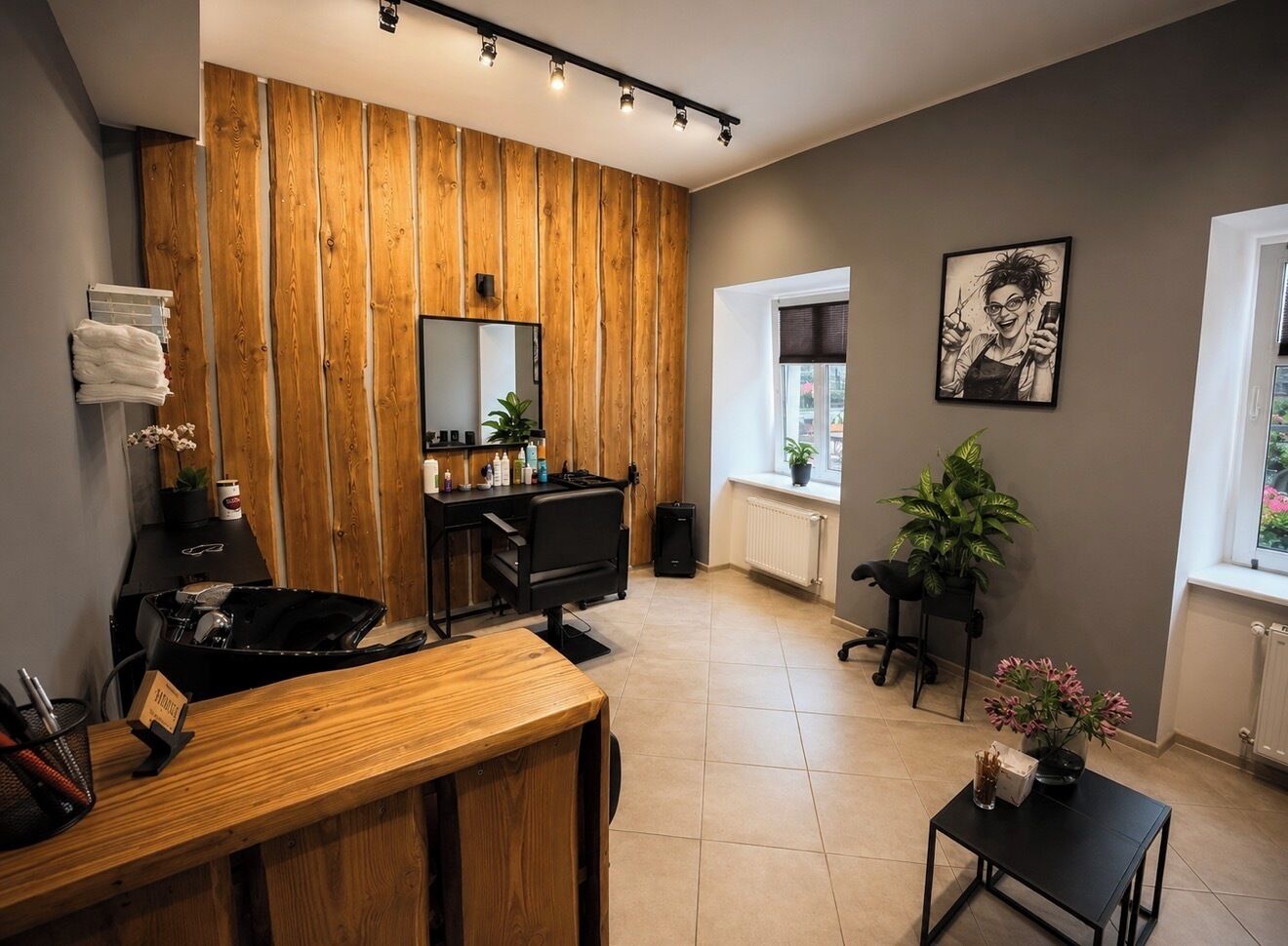 Um interior moderno com uma parede de destaque em madeira, um balcão de recepção, uma cadeira de escritório preta, uma planta em vaso e uma janela com vista.