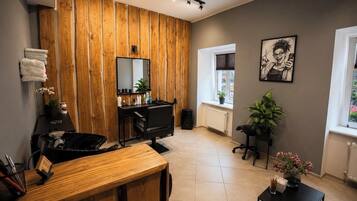Um interior moderno com uma parede de destaque em madeira, um balcão de recepção, uma cadeira de escritório preta, uma planta em vaso e uma janela com vista.