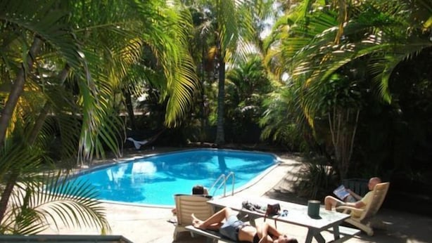 Uma área de piscina com cadeiras de espreguiçadeira e uma pessoa deitada em uma delas.
