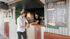 Um food truck com um quadro de menu exibindo hambúrgueres, saladas e acompanhamentos.
