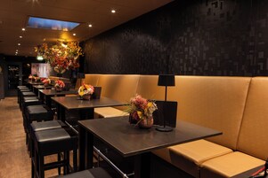 Um restaurante com várias mesas e cabines, cada uma com um vaso de flores.