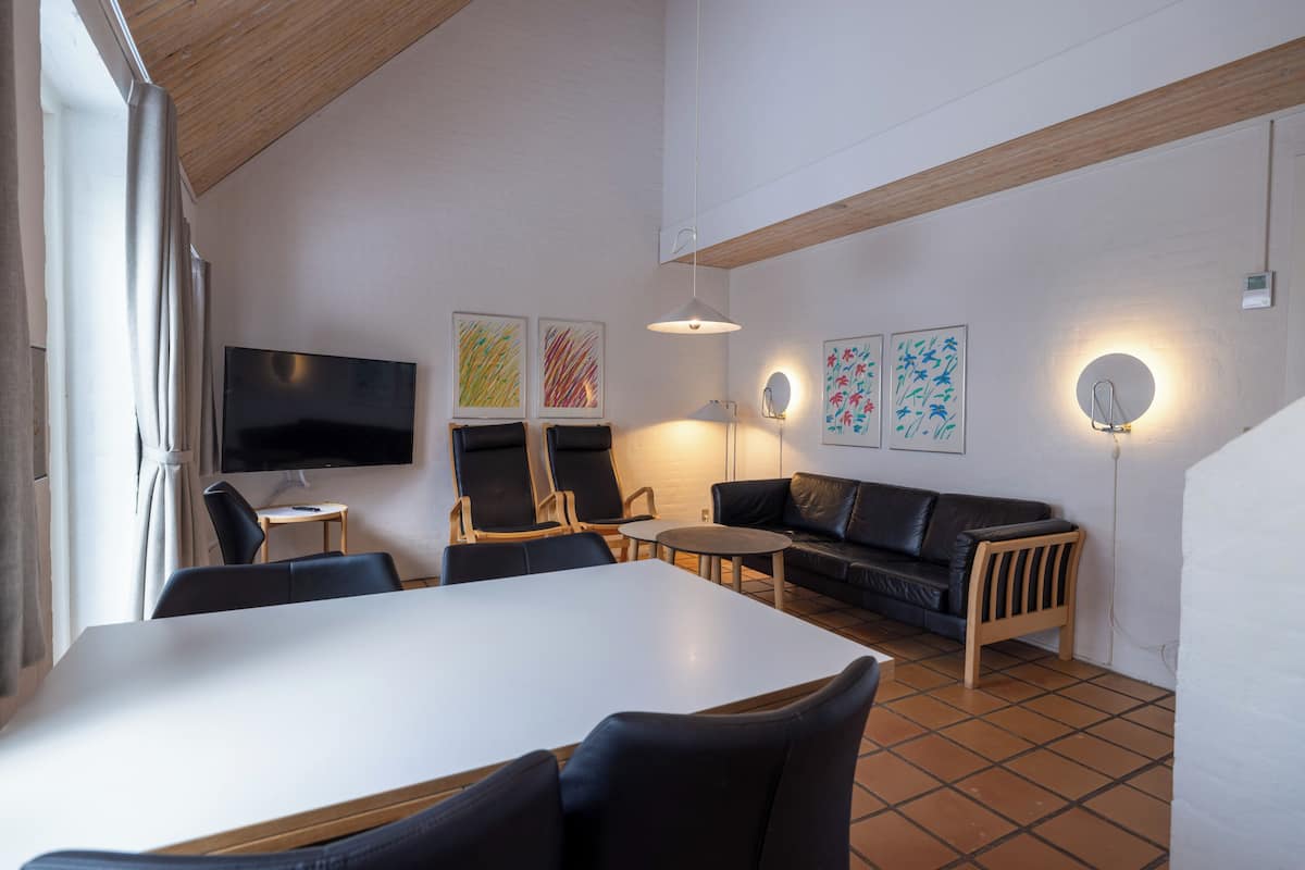Uma sala de estar moderna com uma televisão de tela grande, uma mesa de jantar e assentos confortáveis.