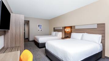 Quarto de hotel com duas camas, televisão, escrivaninha e cadeira.