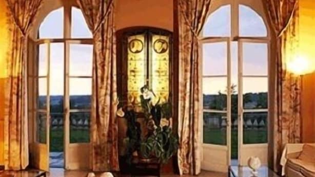 Um quarto com grandes janelas em arco, um relógio e vista para o exterior.
