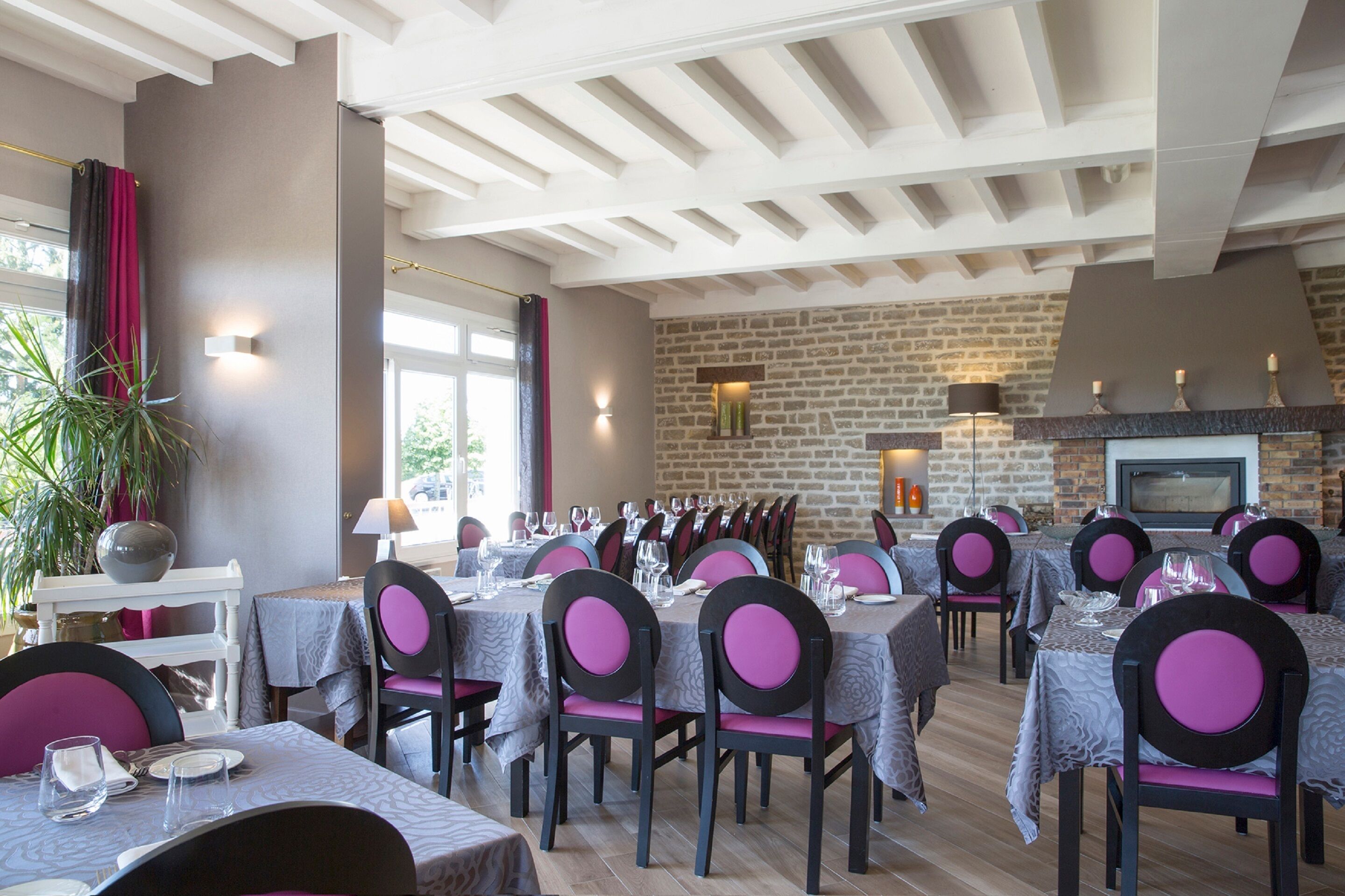 Restaurante com várias mesas e cadeiras, uma parede de tijolos e uma lareira.